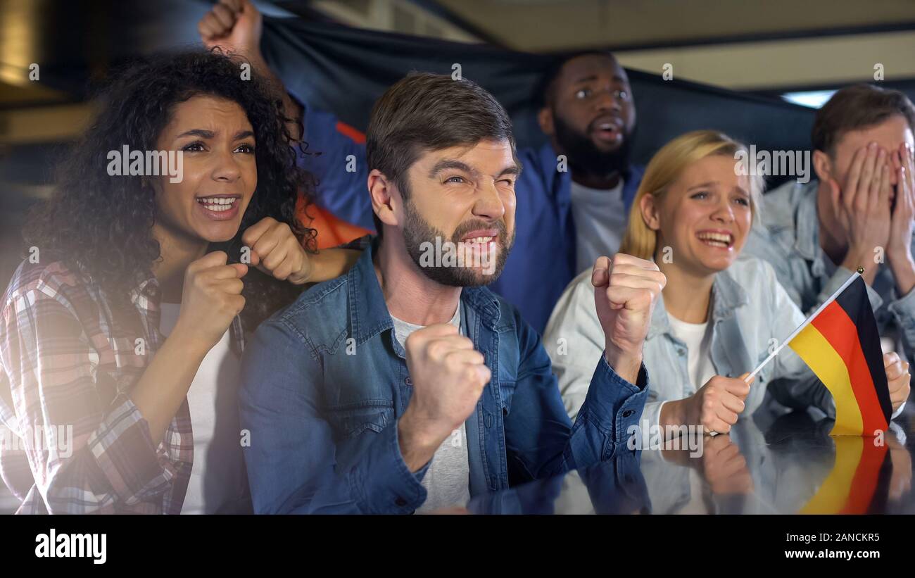 Anxious football fans with german flag supporting national team in ...