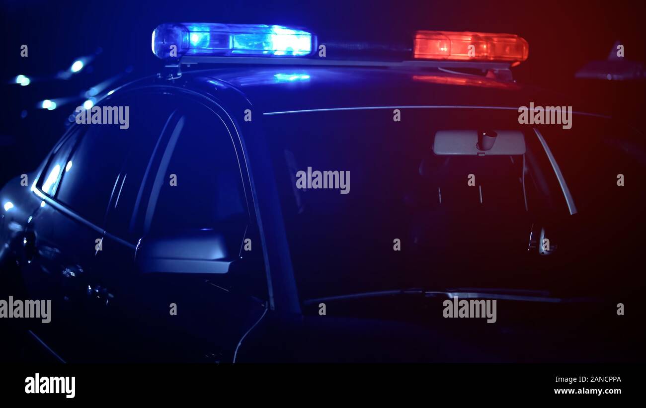 Empty police car with flashing lights standing on road, officers ...
