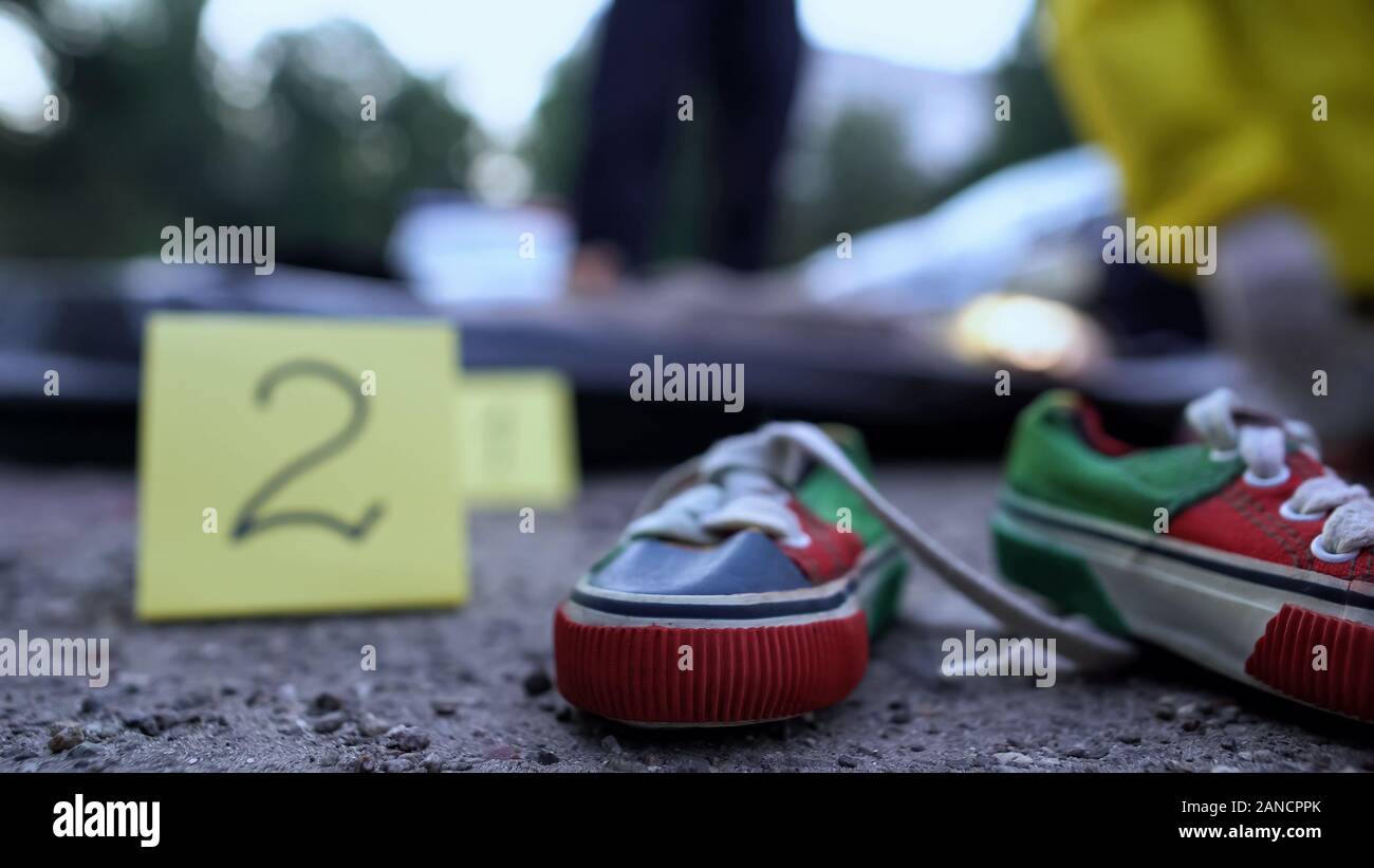 Child snickers marking as evidence, experts working on crime scene, car ...