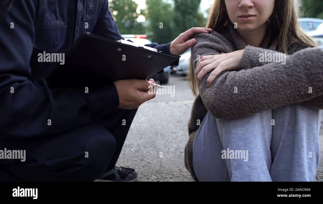 Officer trying to calm down female victim of car accident, shocked girl ...