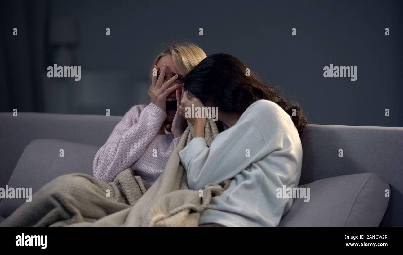 Two beautiful scared girls watching horror movie at night, frightening ...