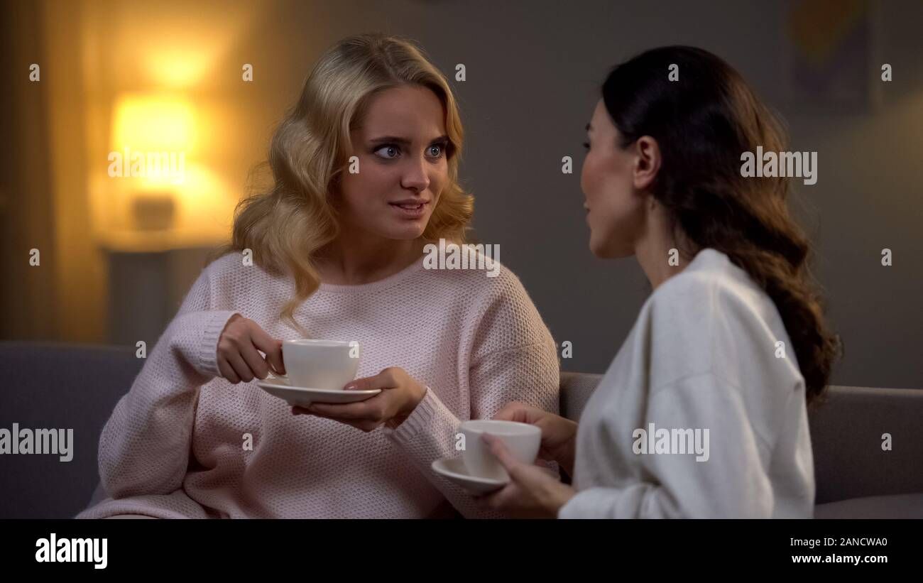 Two female friends drinking tea at home and talking about life ...