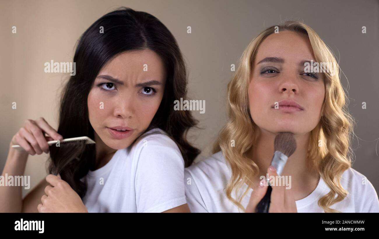 Two girls applying make up, fighting for place in front of mirror ...