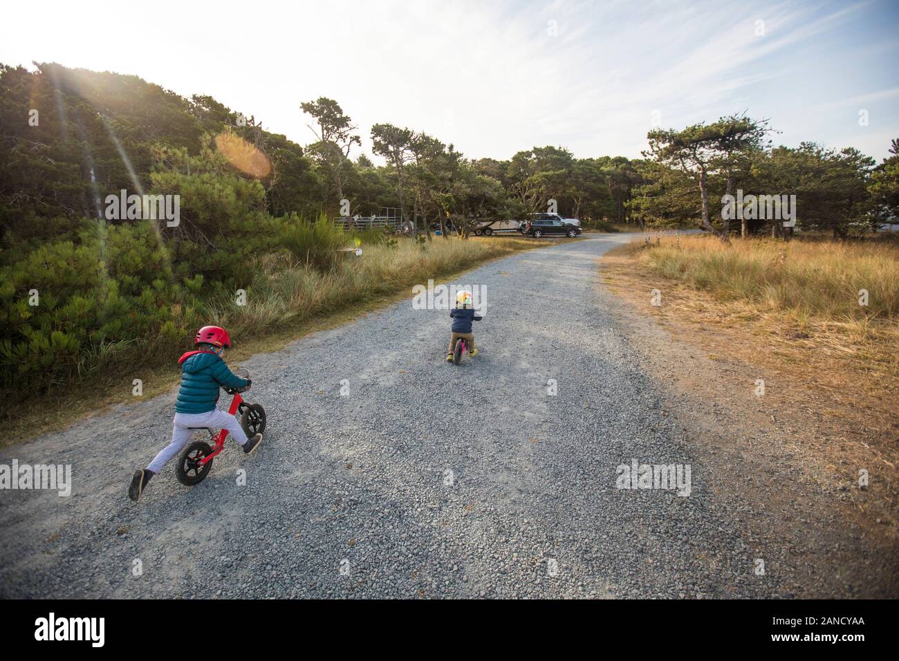 Rear view of brother and sister biking on gravel road at dawn Stock ...