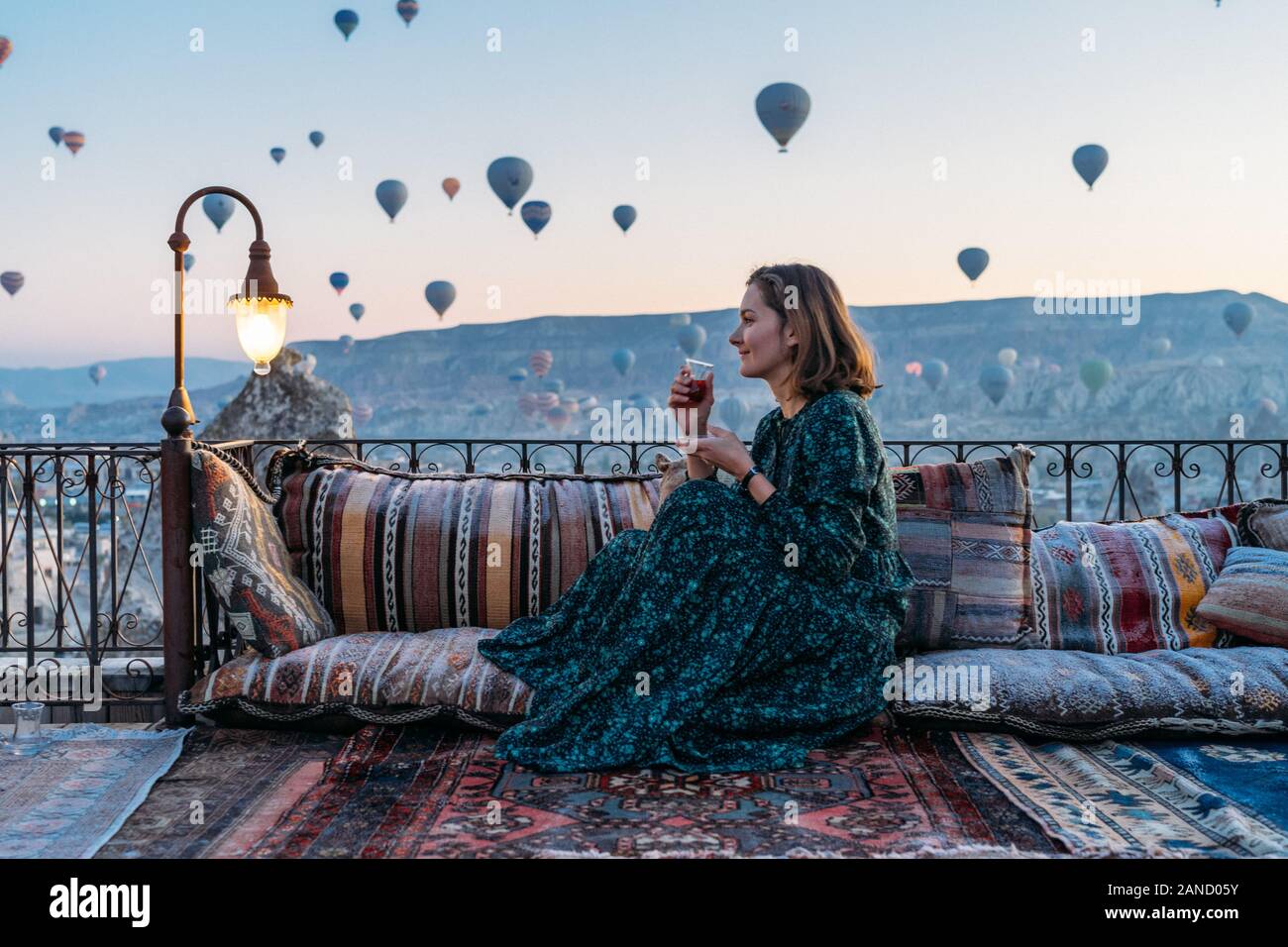 Woman drinking early morning tea with hot air balloons in Cappadocia ...
