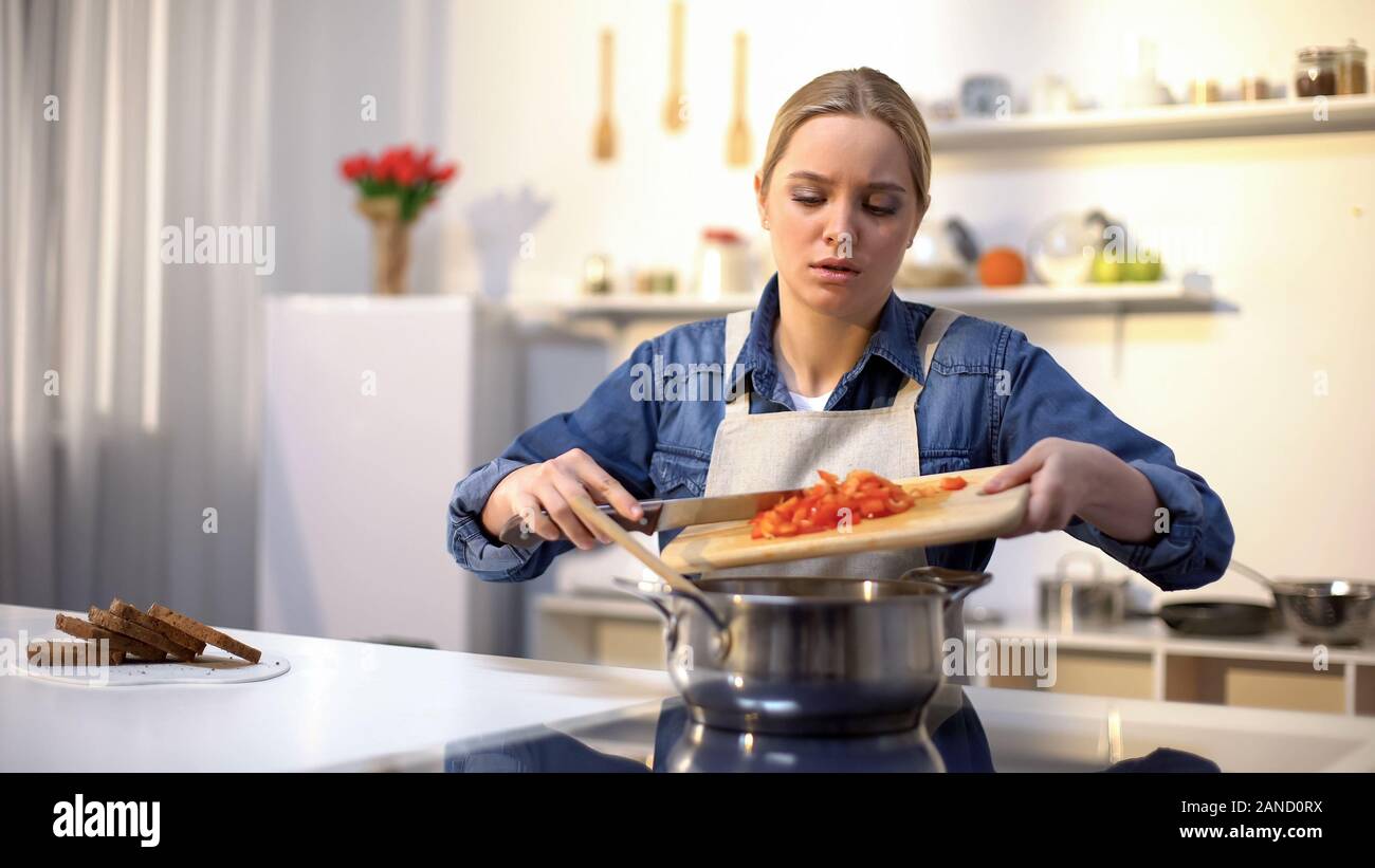 Young beautiful woman unhappy with cooking in kitchen, bored and tired ...