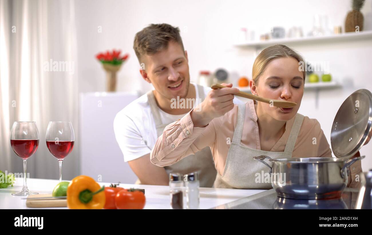 Happy couple cooking together in kitchen, female tasting soup, healthy ...