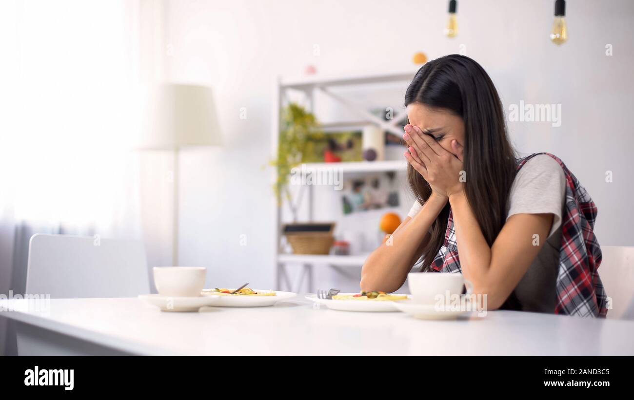 Young sad woman sitting alone in kitchen and crying after quarrel ...