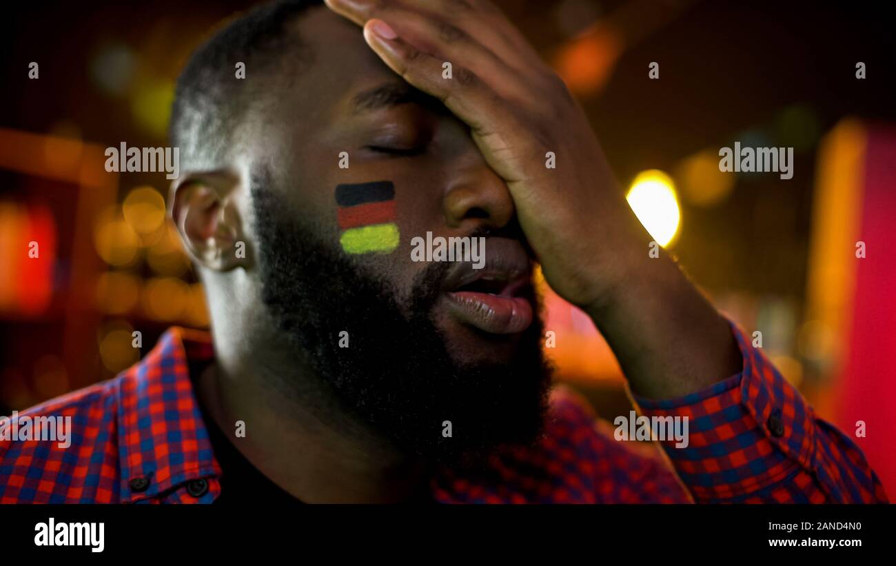 Disappointed german football fan with flag on cheek making facepalm ...