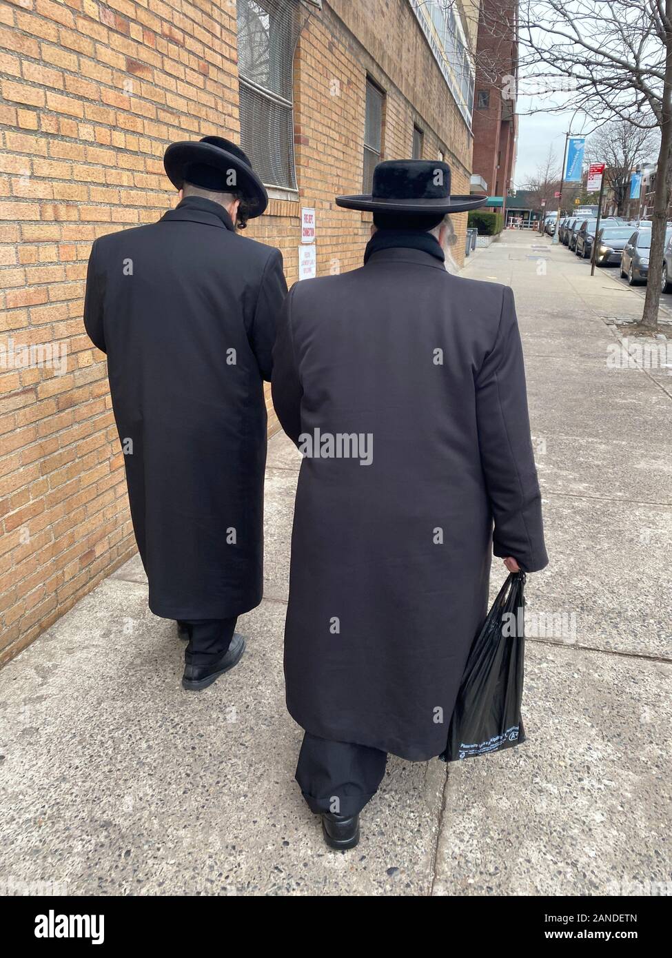 Two older orthodox Jewish men walk up the street in Borough Park, known ...