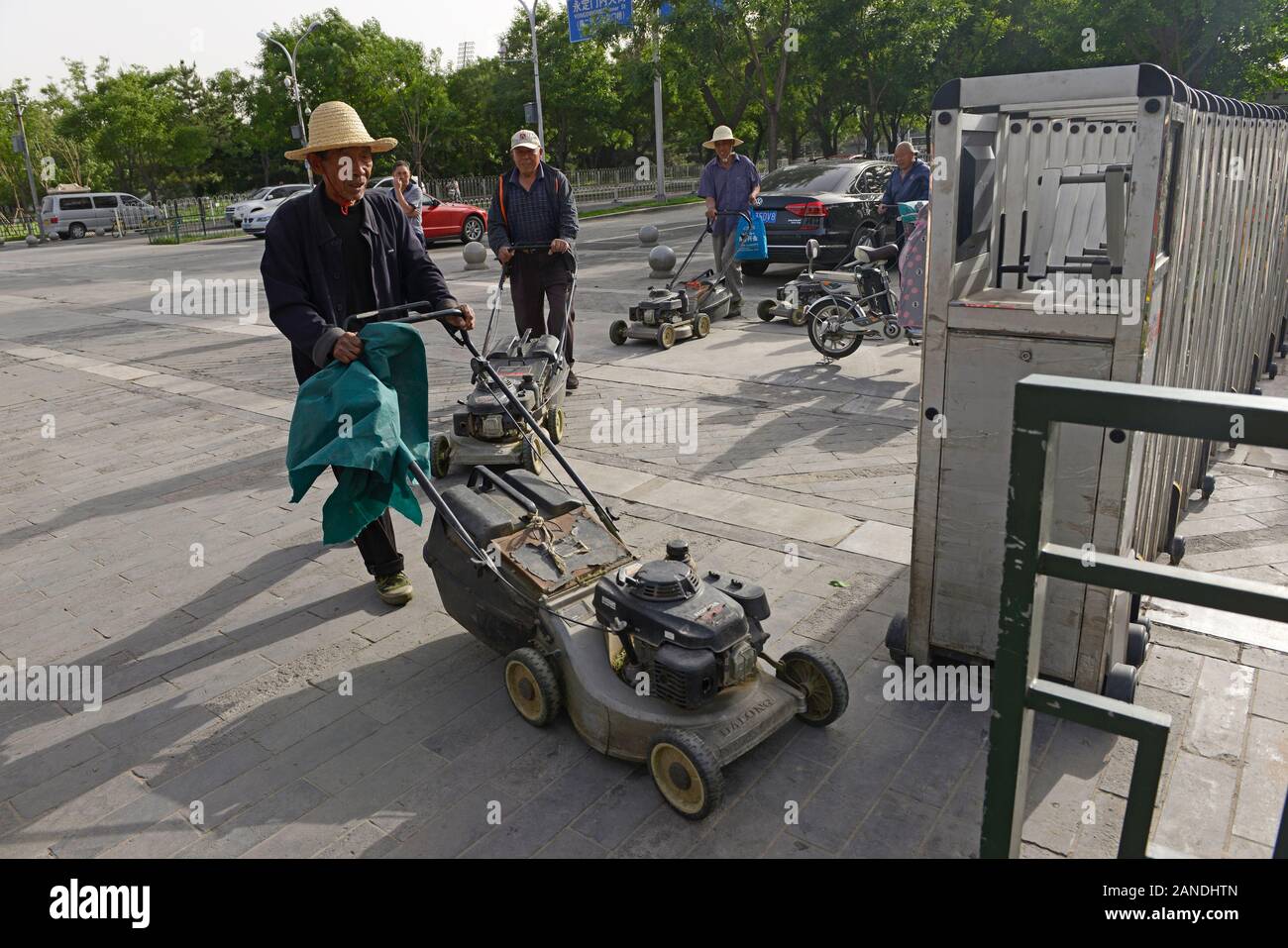 Gardeners push their mowers through a gate and into a park in southern ...