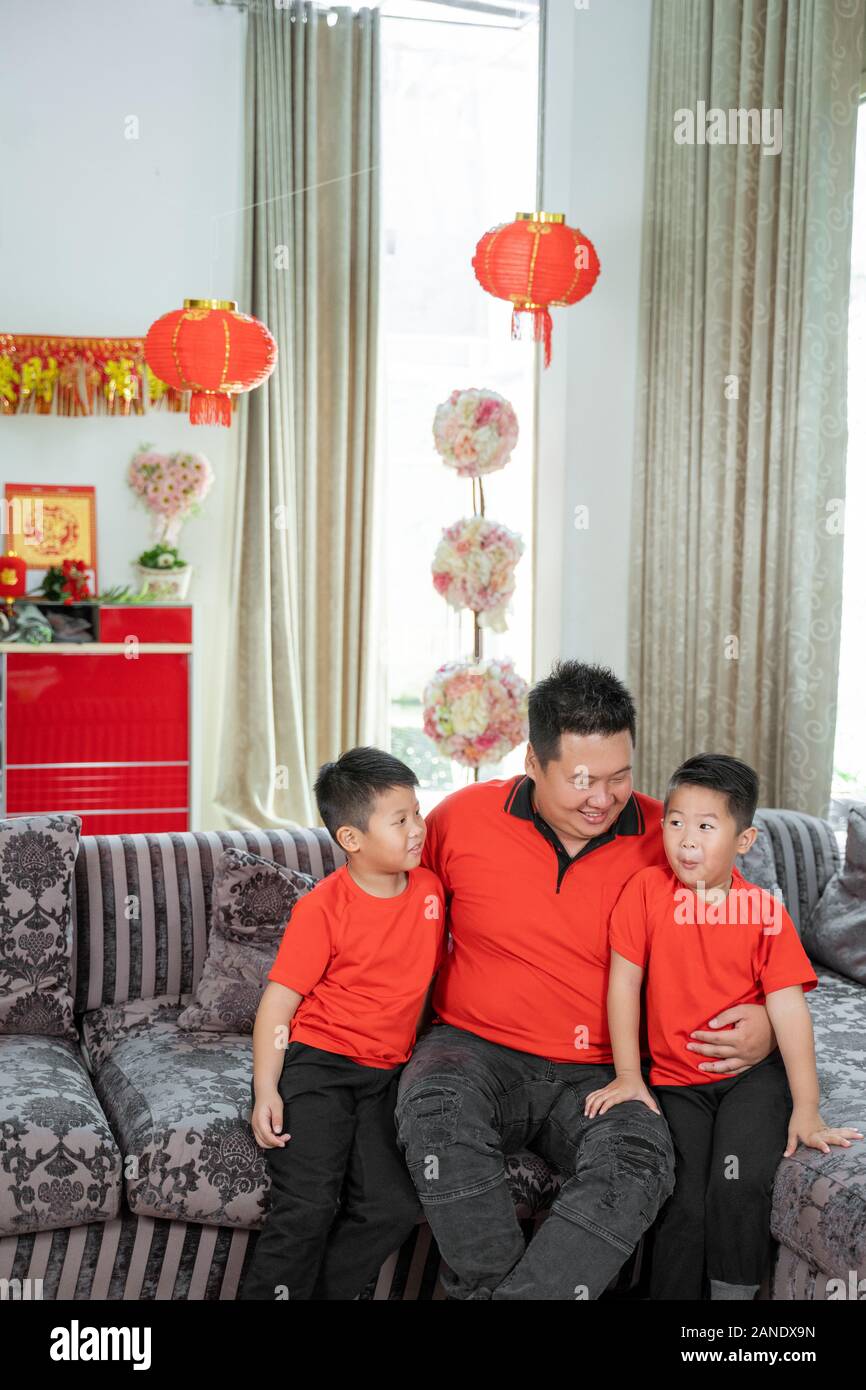 Smiling asian chinese father and two son wearing red theme clothing ...