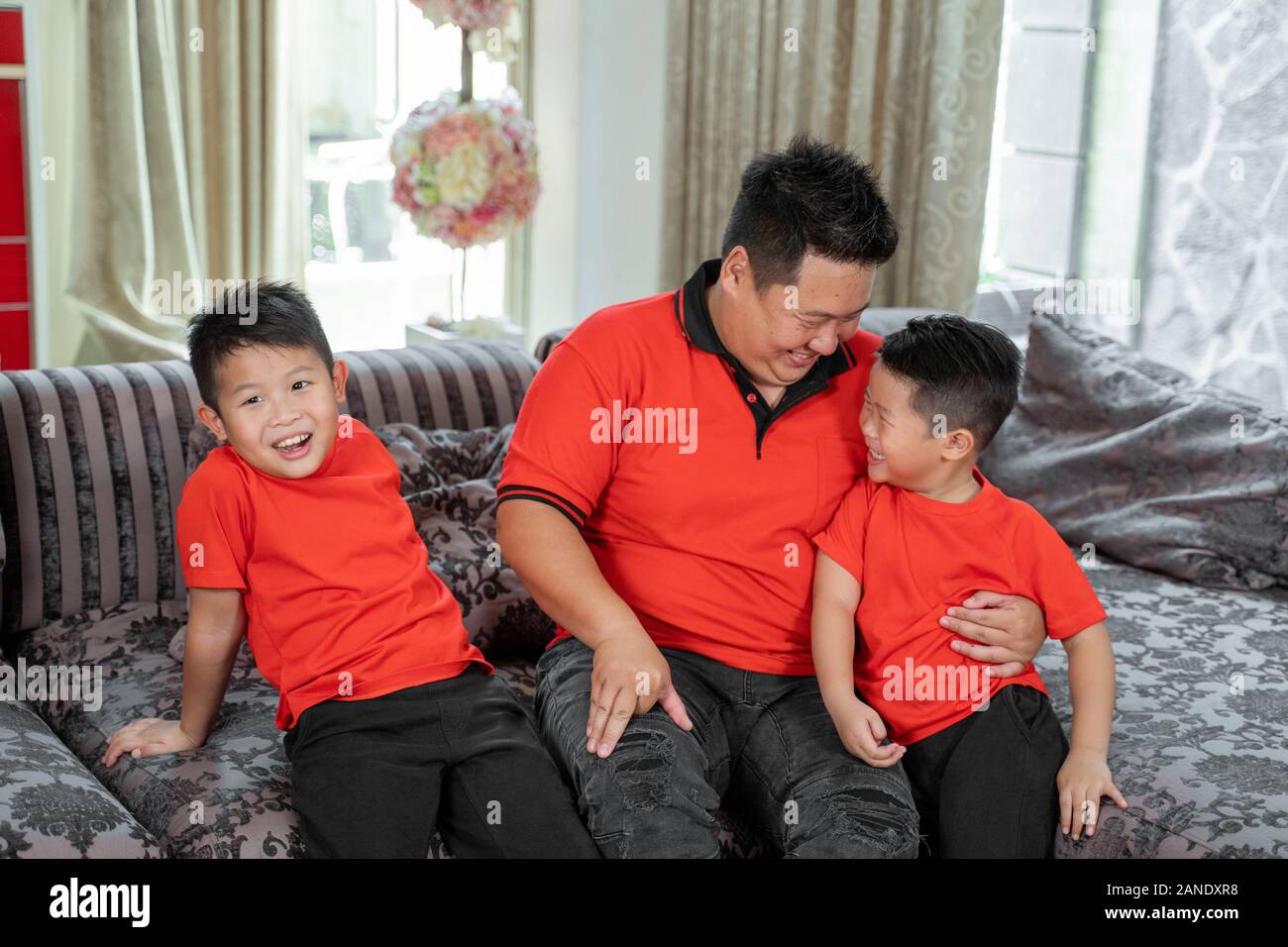 Smiling asian chinese father and two son wearing red theme clothing ...