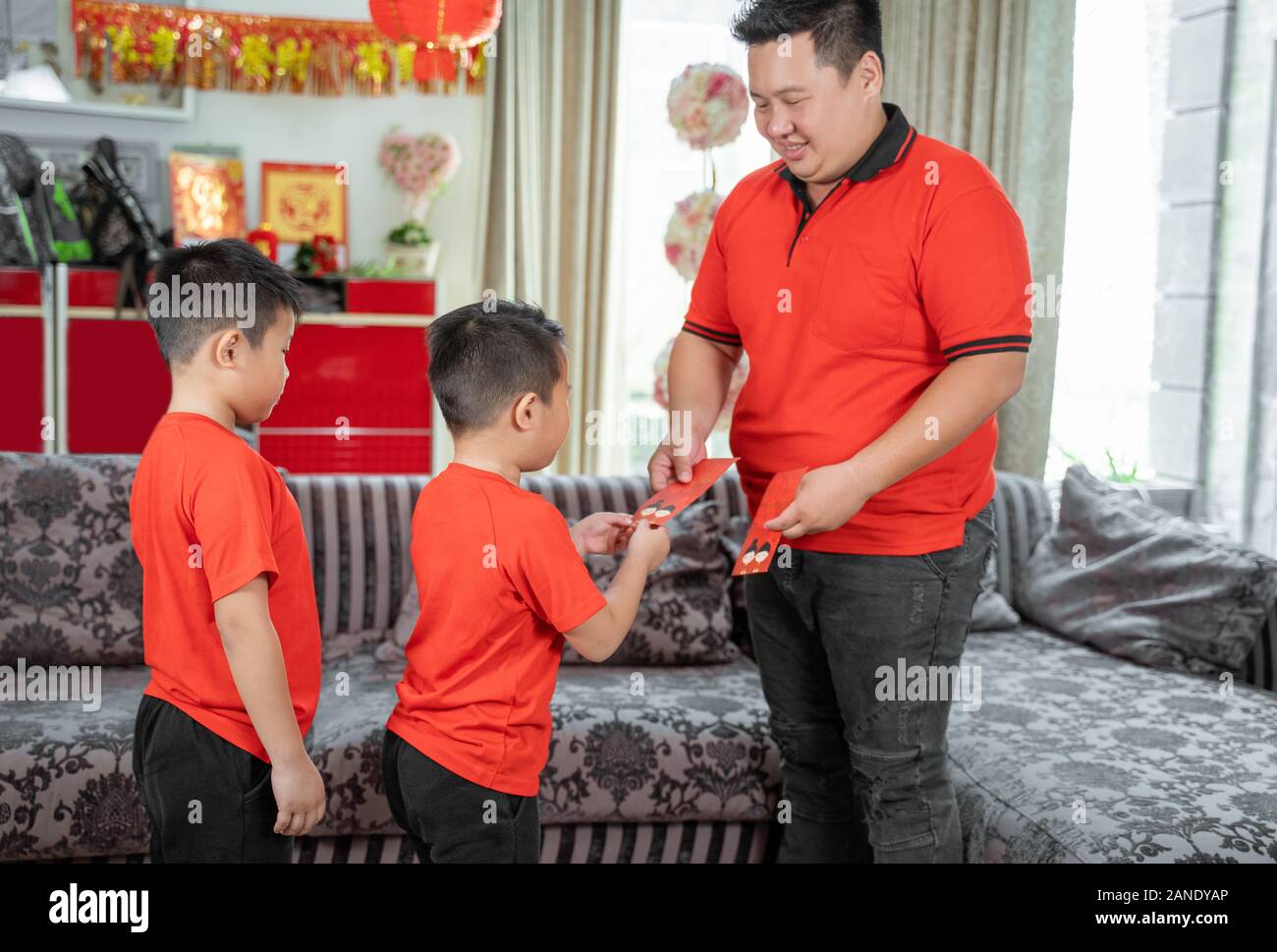 Asian father give ang pao to her son Stock Photo - Alamy