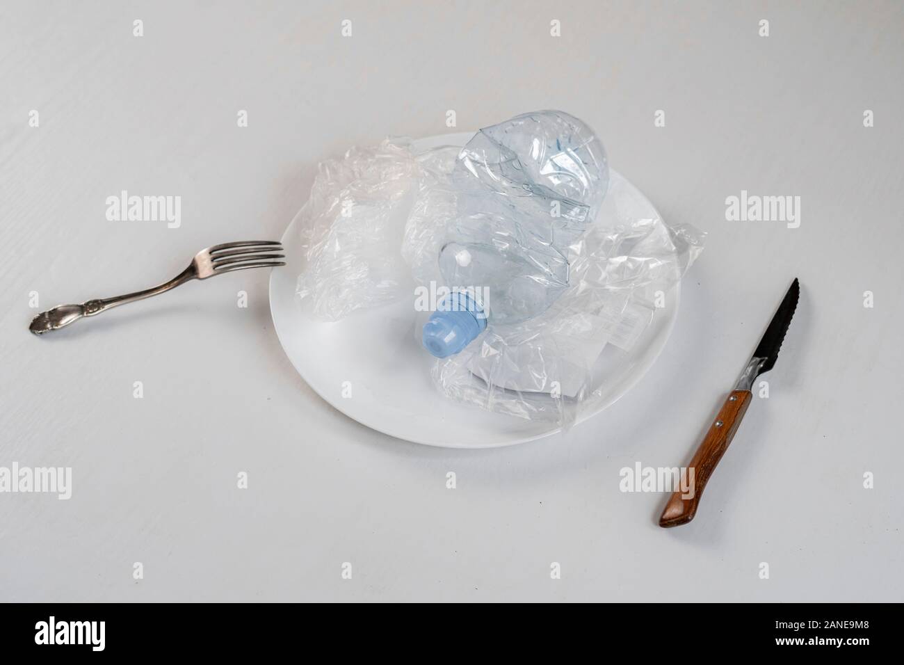 a top view of plastic waste garbage in the white plate, knife and fork ...