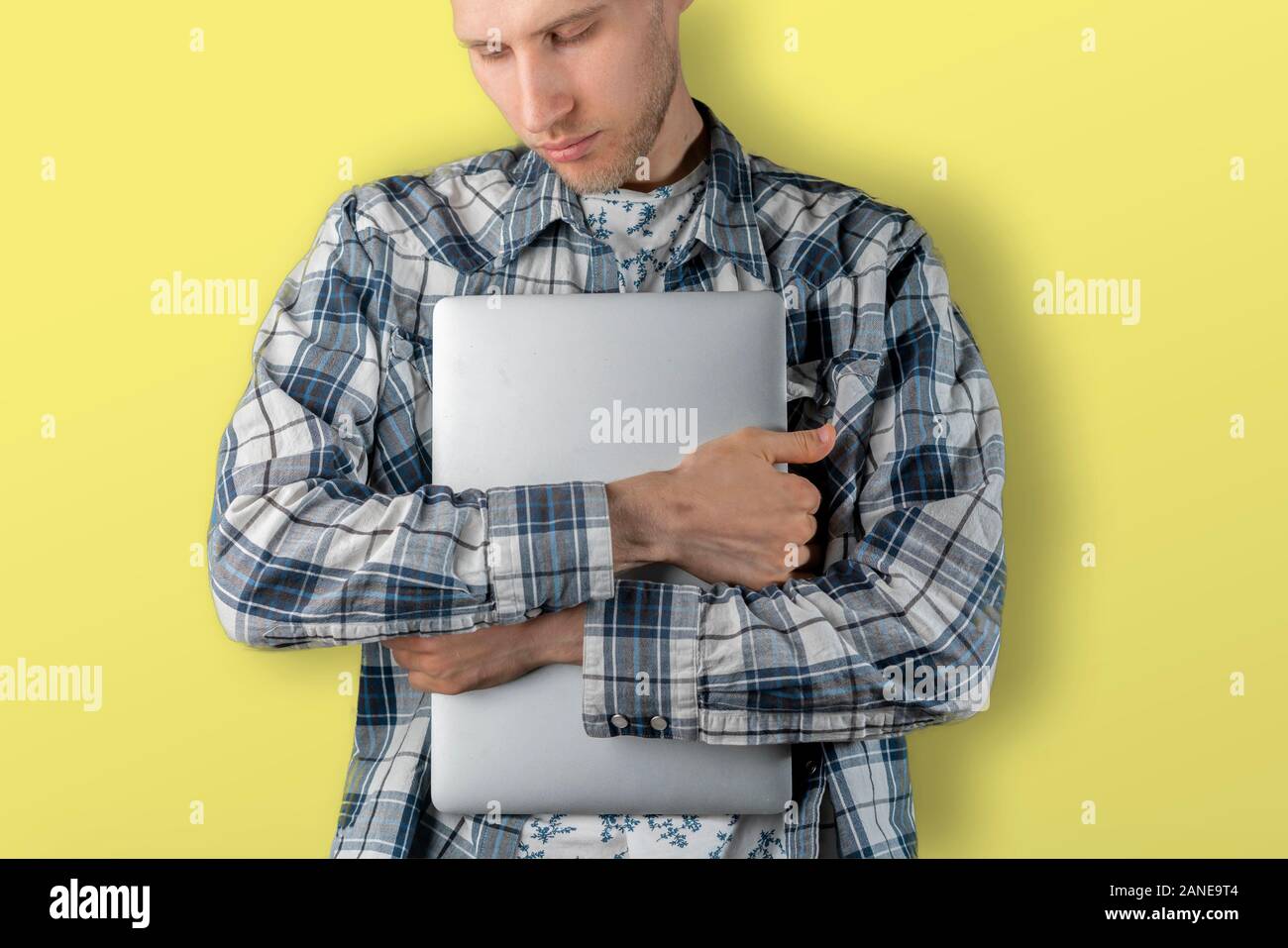 a man holding and carrying the laptop, hug the cumputer standing ...