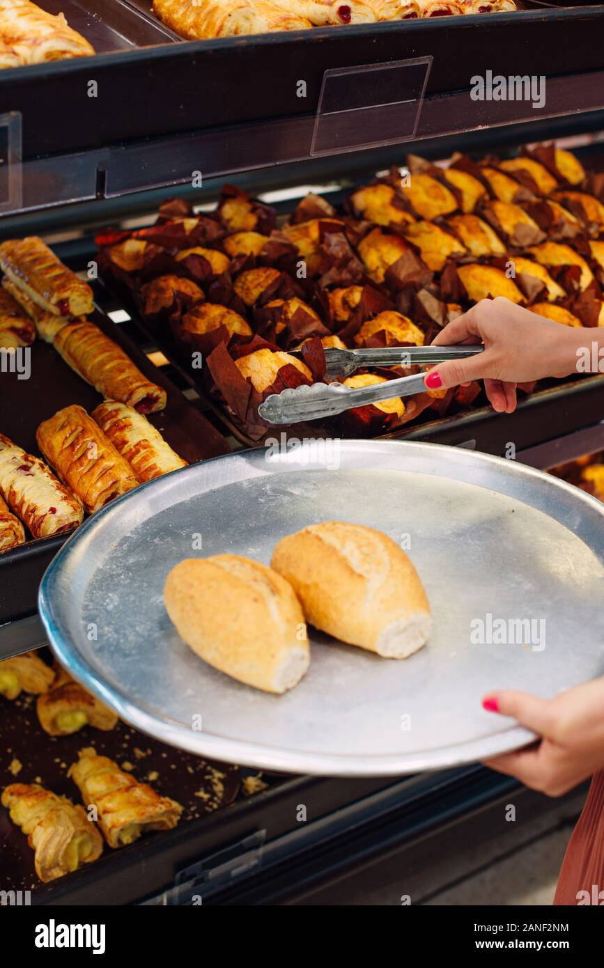 women choosing bread at the supermarket. bun tongs and tray Stock Photo ...