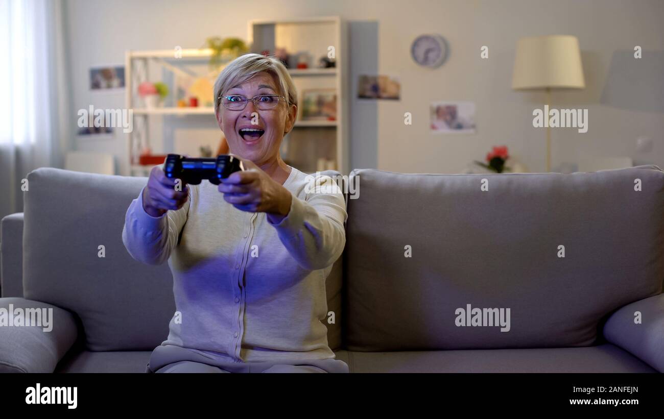 Excited old woman playing video game on joystick, rejoicing victory ...