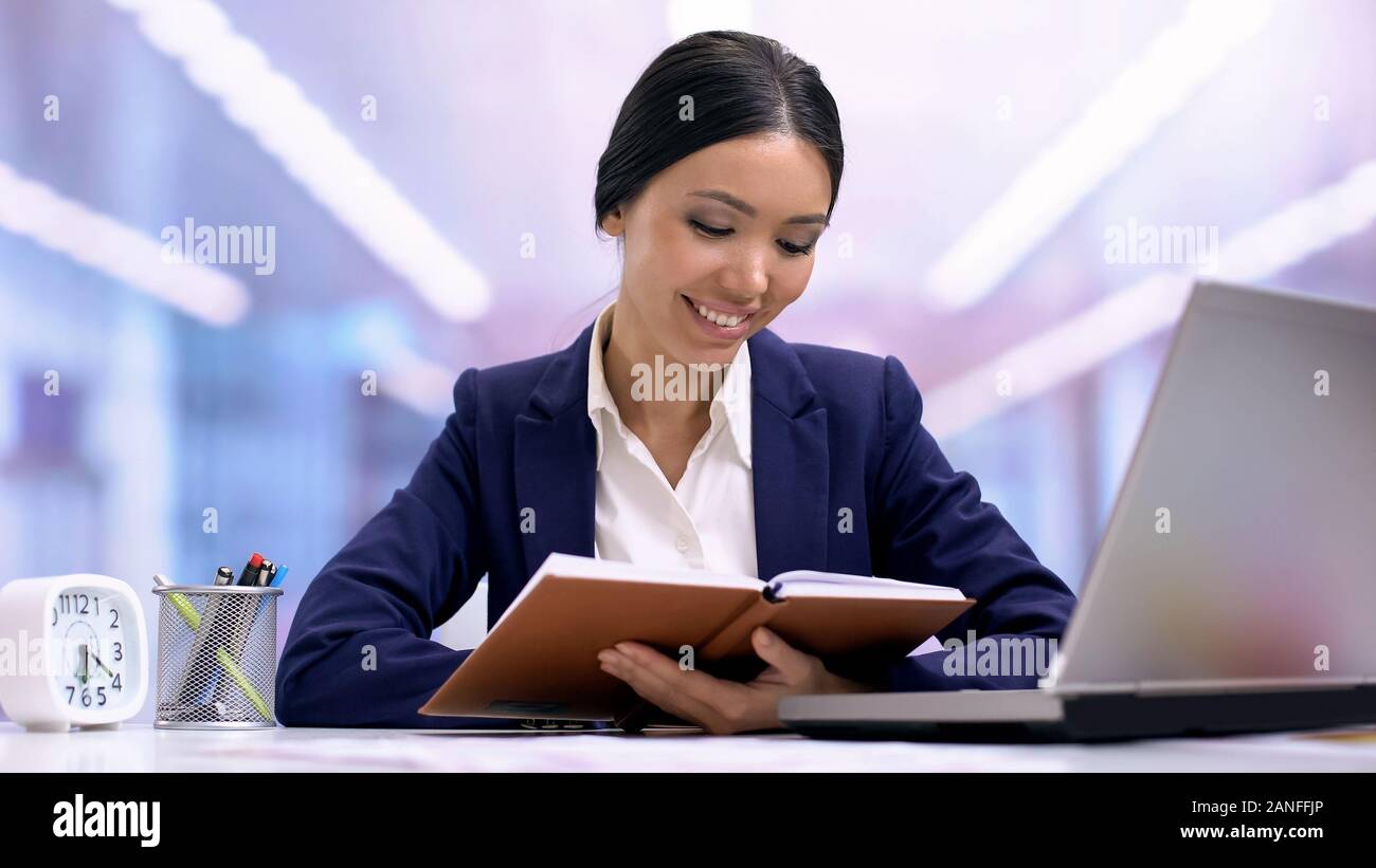 Young female employee writing in notebook, planning work day, ideas ...