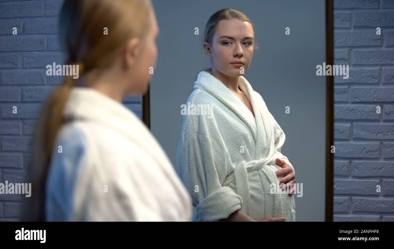 Pregnant woman looking in mirror reflection, expecting baby birth ...