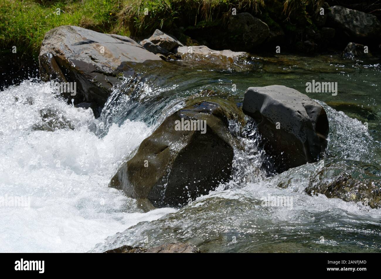 Water runs over the top of a boulder into frothy white water below ...