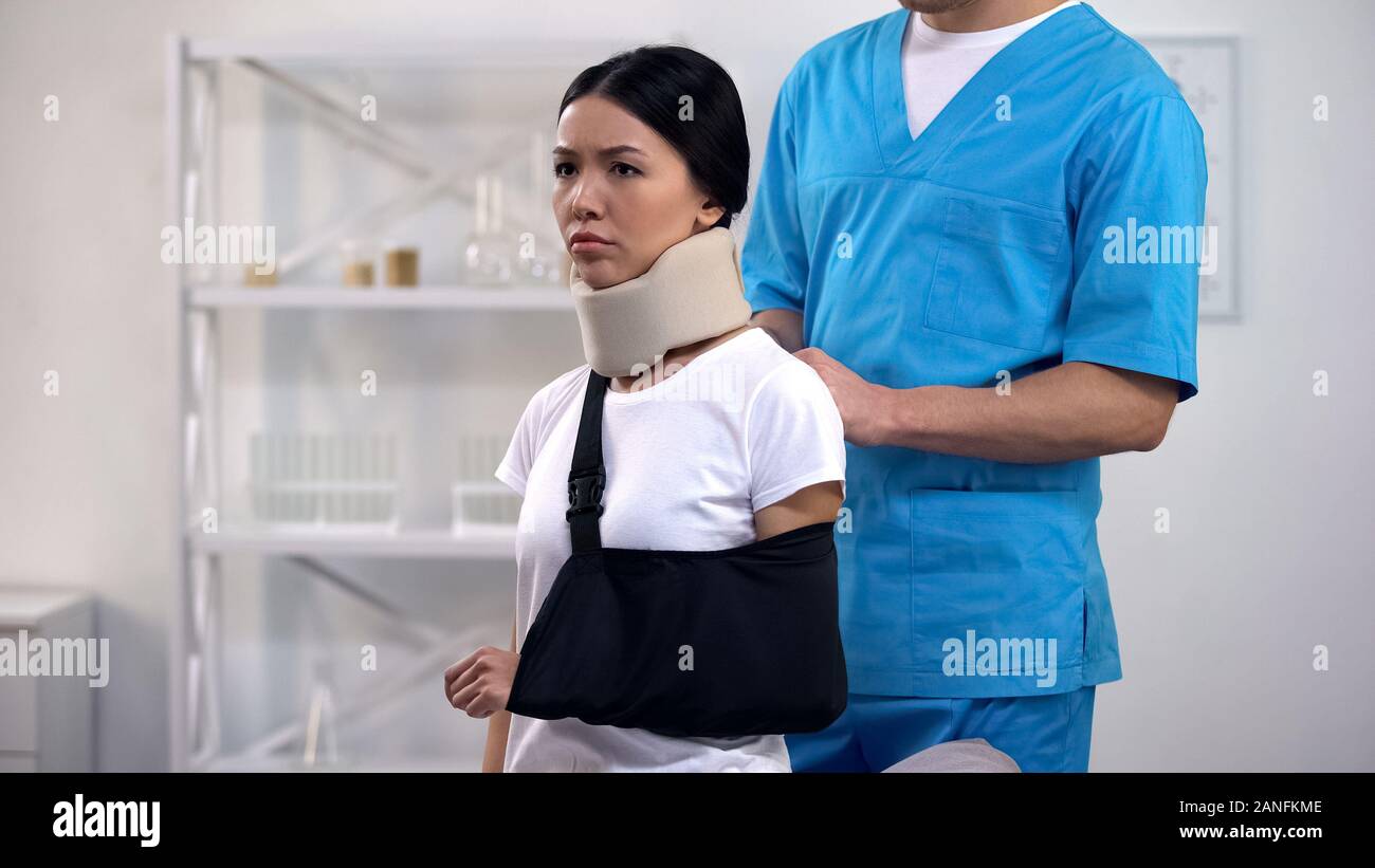 Professional male surgeon fixing arm sling upset patient in foam ...