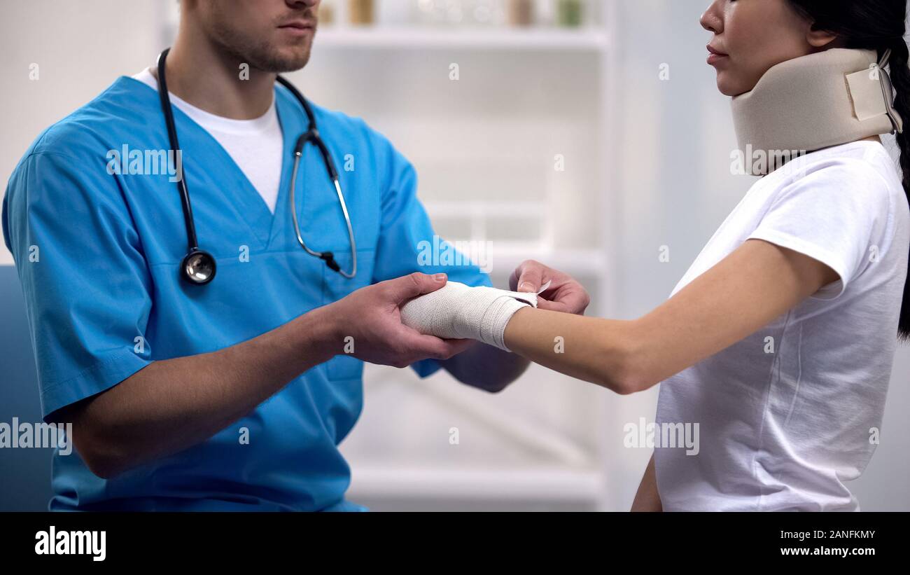 Doctor fixing wrist elastic wrap female patient in foam cervical collar ...