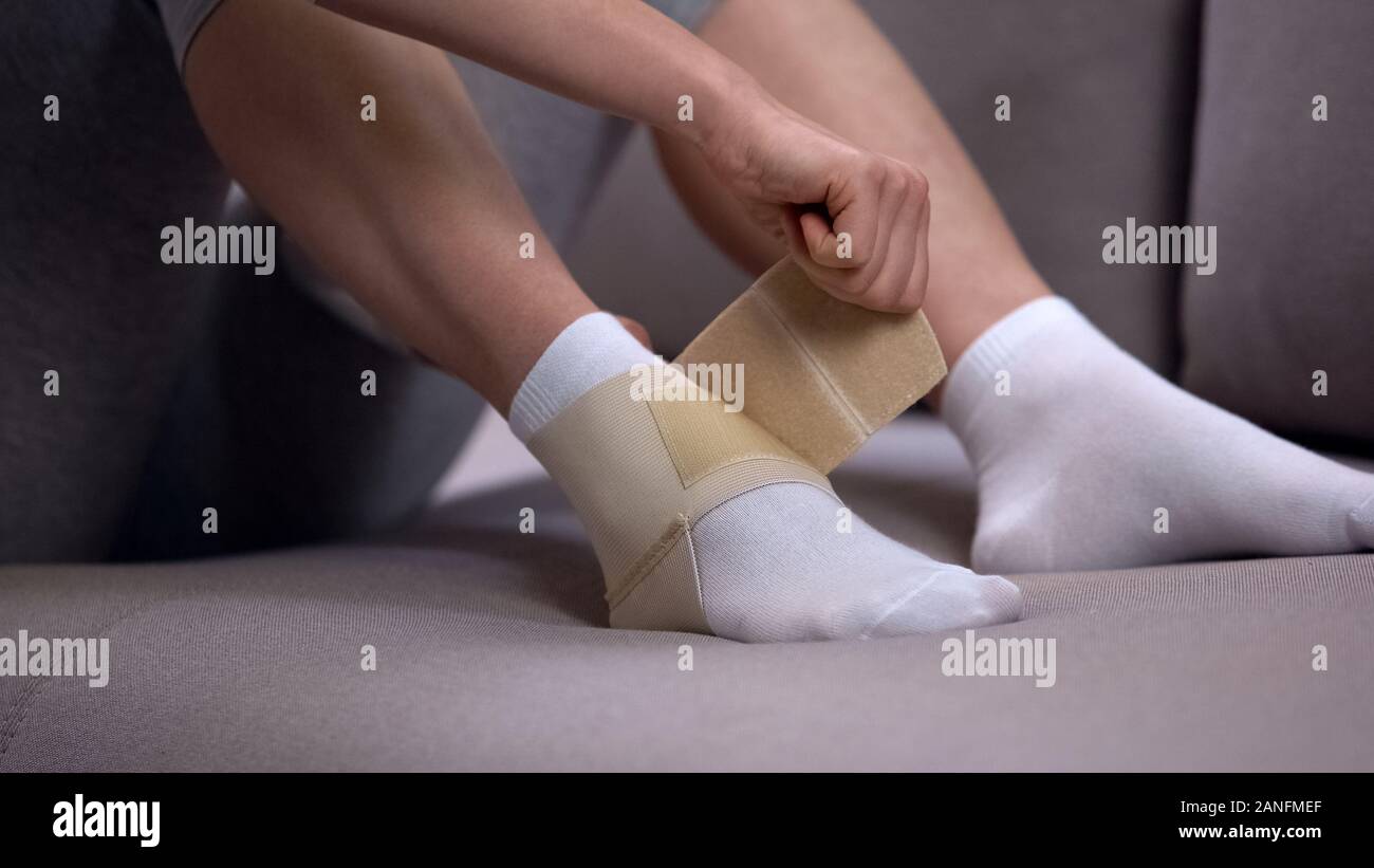 Woman fixing two-strap ankle wrap in proper position, sprained joint ...
