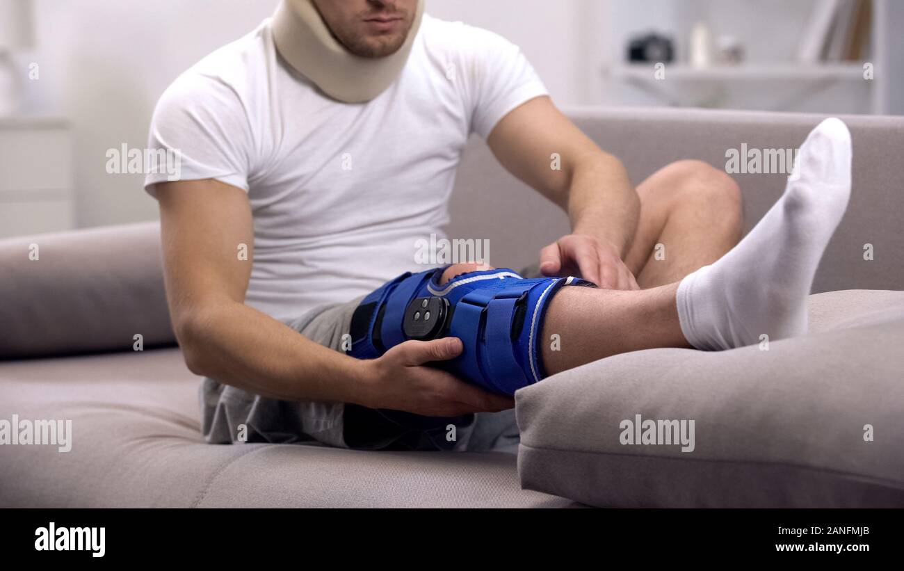 Injured man in foam cervical collar checking neoprene knee brace ...
