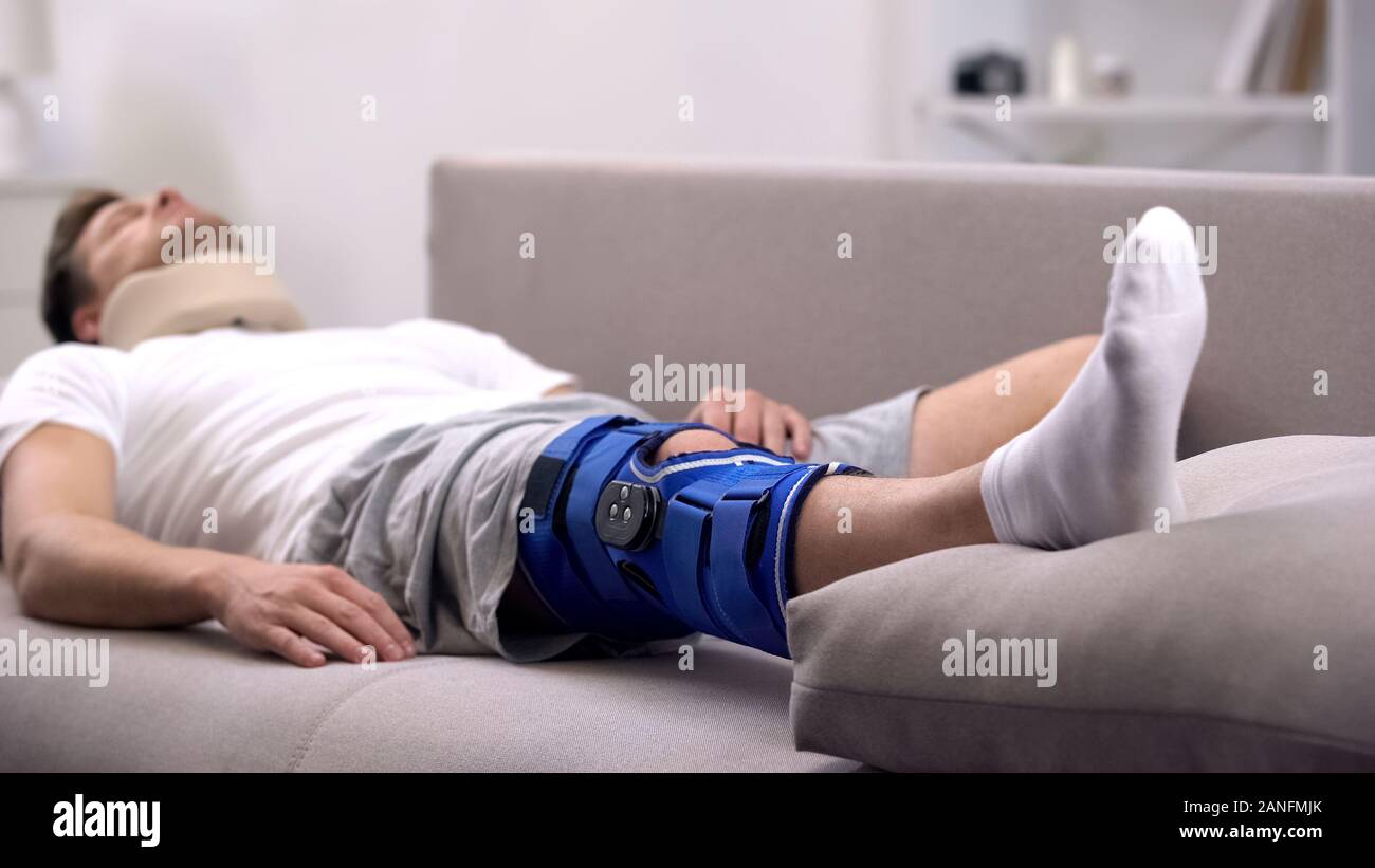 Male in foam cervical collar and neoprene knee brace sleeping on sofa ...