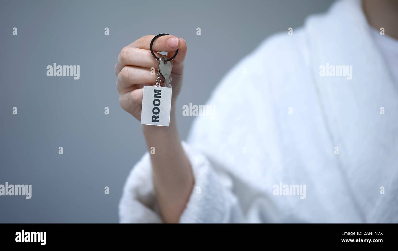 Person in bathrobe holding keys with Room word, health resort ...