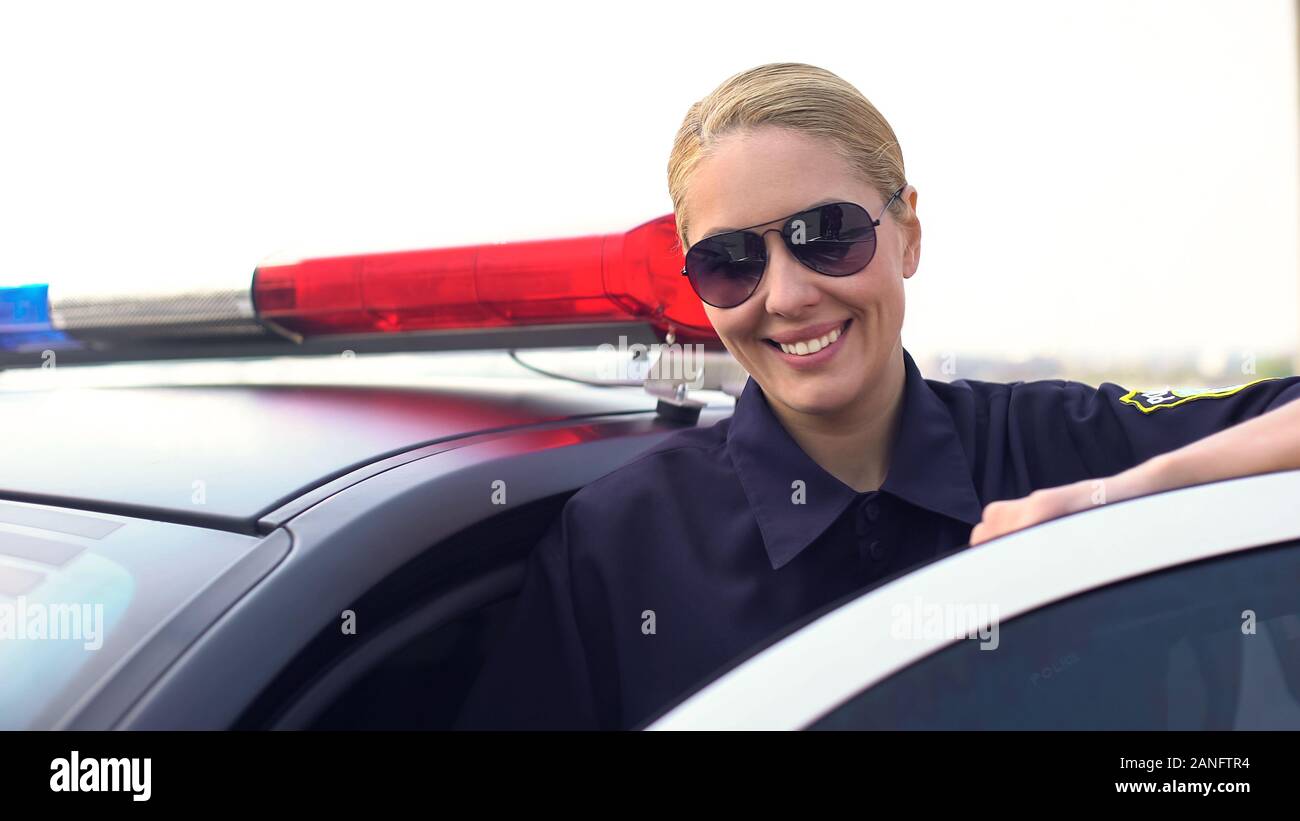 Policewoman in sunglasses smiling, looking into camera, standing near ...