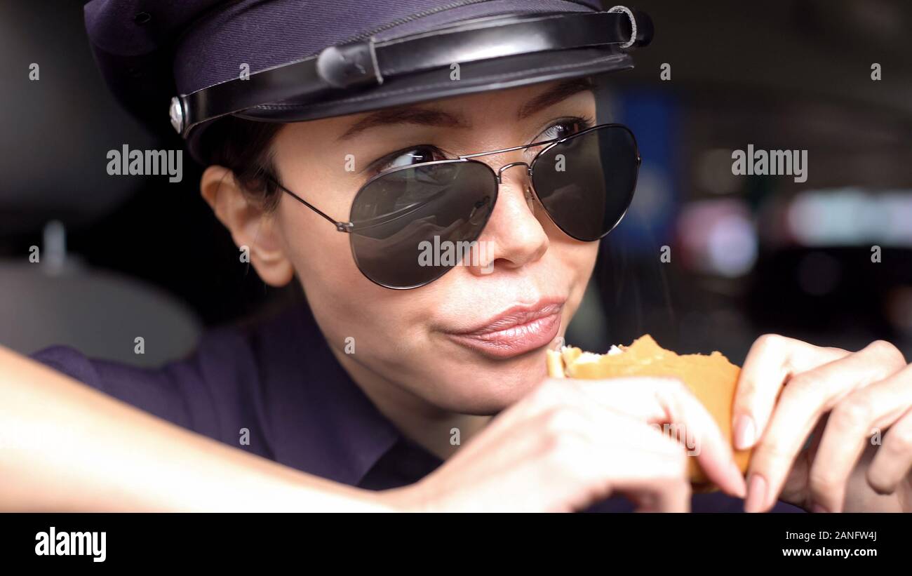 Hungry asian patrolwoman holding burger sitting in police car, greasy ...