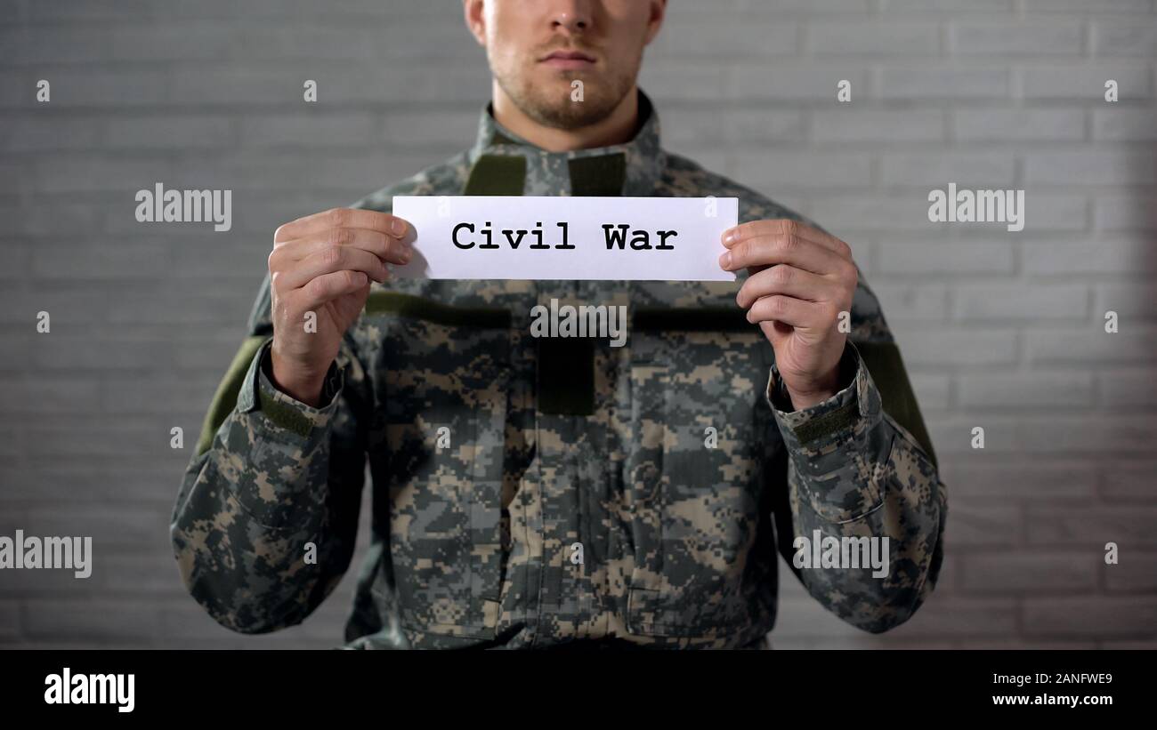 Civil war word written on sign in hands of male soldier, cruelty and ...