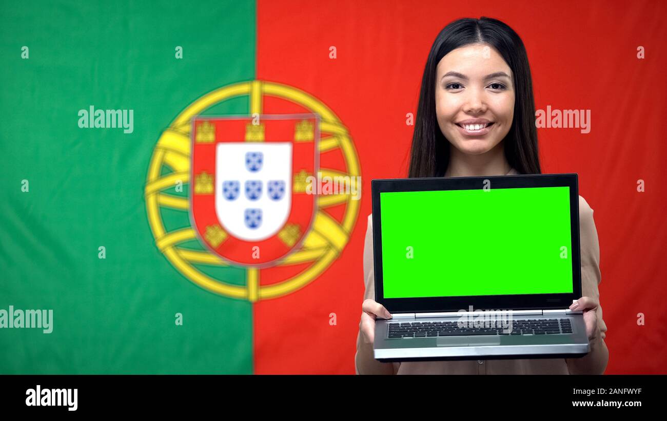 Female student holding laptop with green screen, Portuguese flag on ...