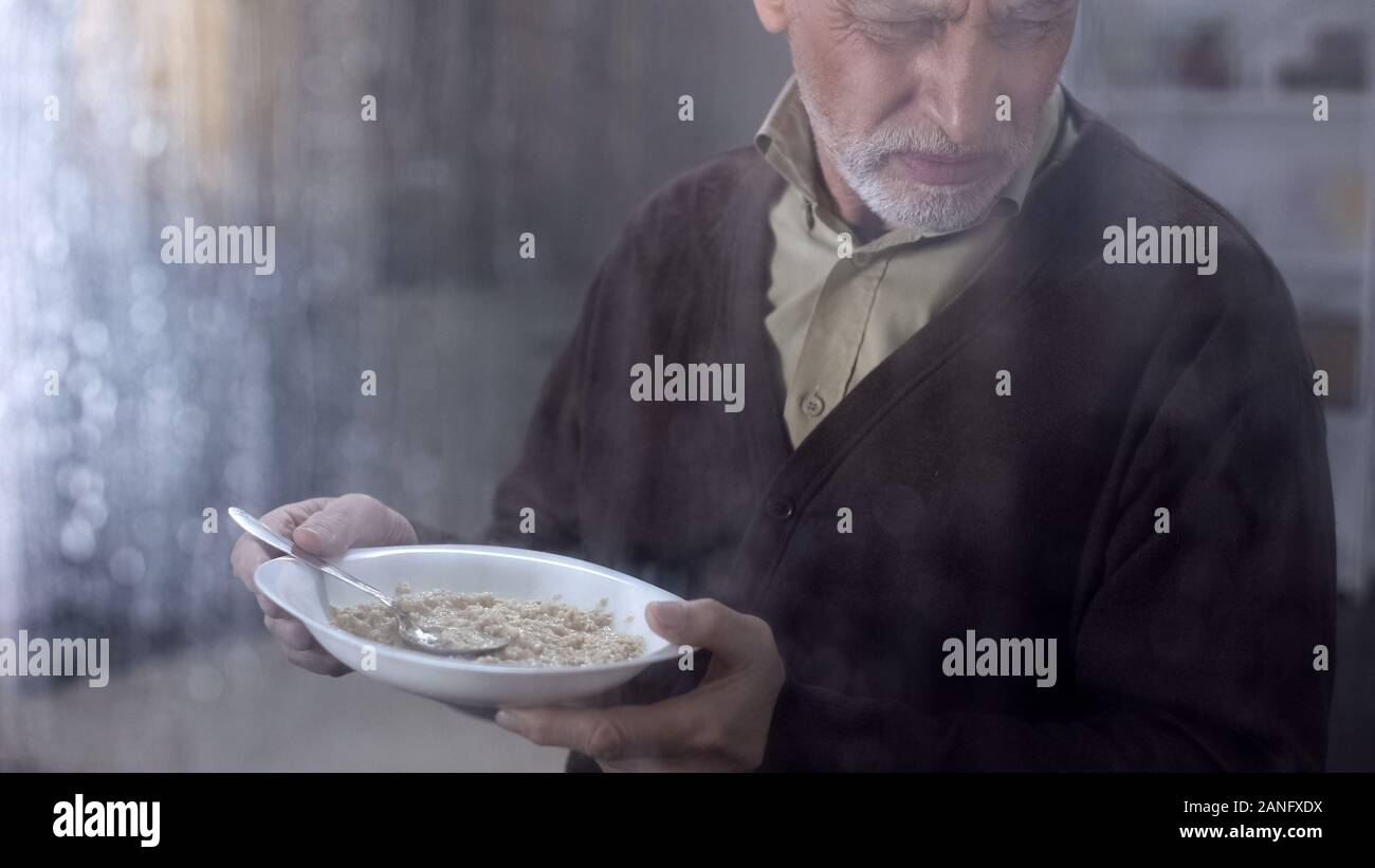 Retired man holding plate with disgusting tasteless oatmeal, lack of ...