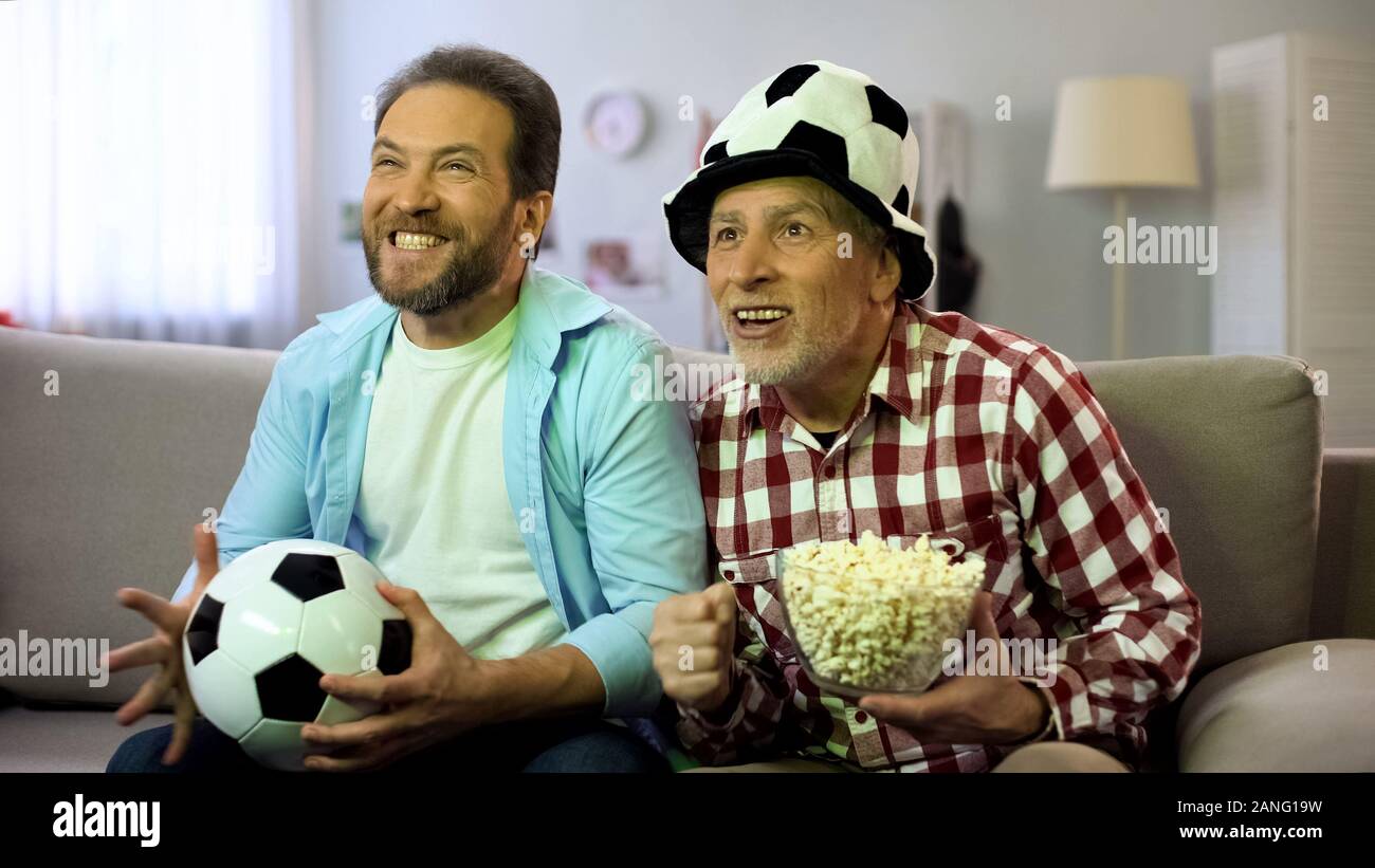 Excited dad and son cheering for favorite football team, watching game ...