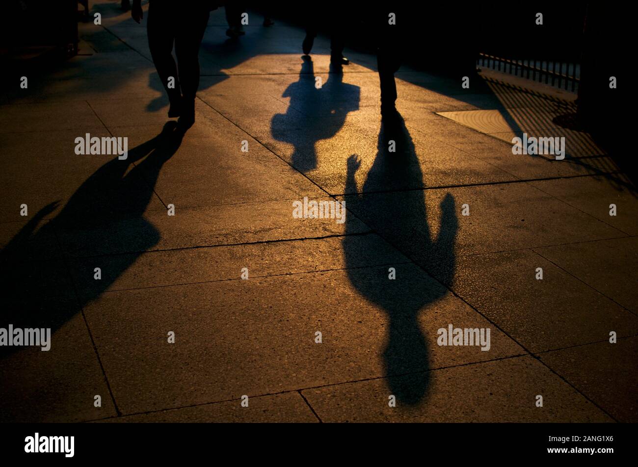 Abstract shadows of people walking on a sidewalk during sunset in ...
