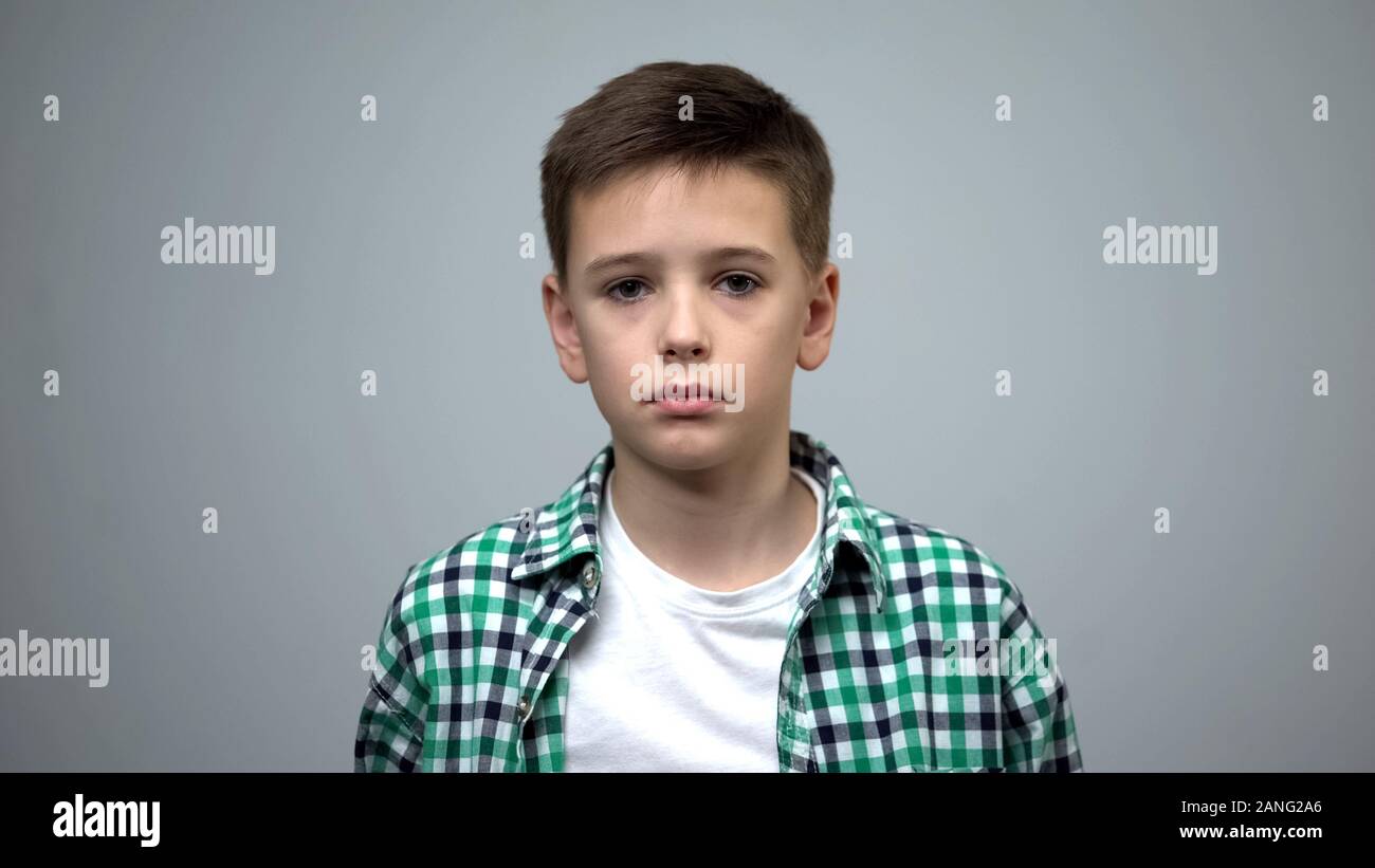 Little pale boy sadly looking into camera, victim of bullying ...