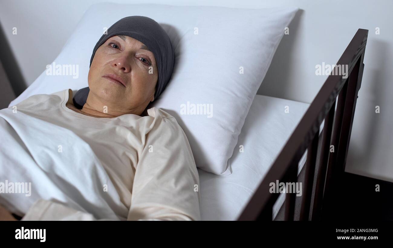 Hopeless female patient suffering cancer lying in sickbed and looking ...