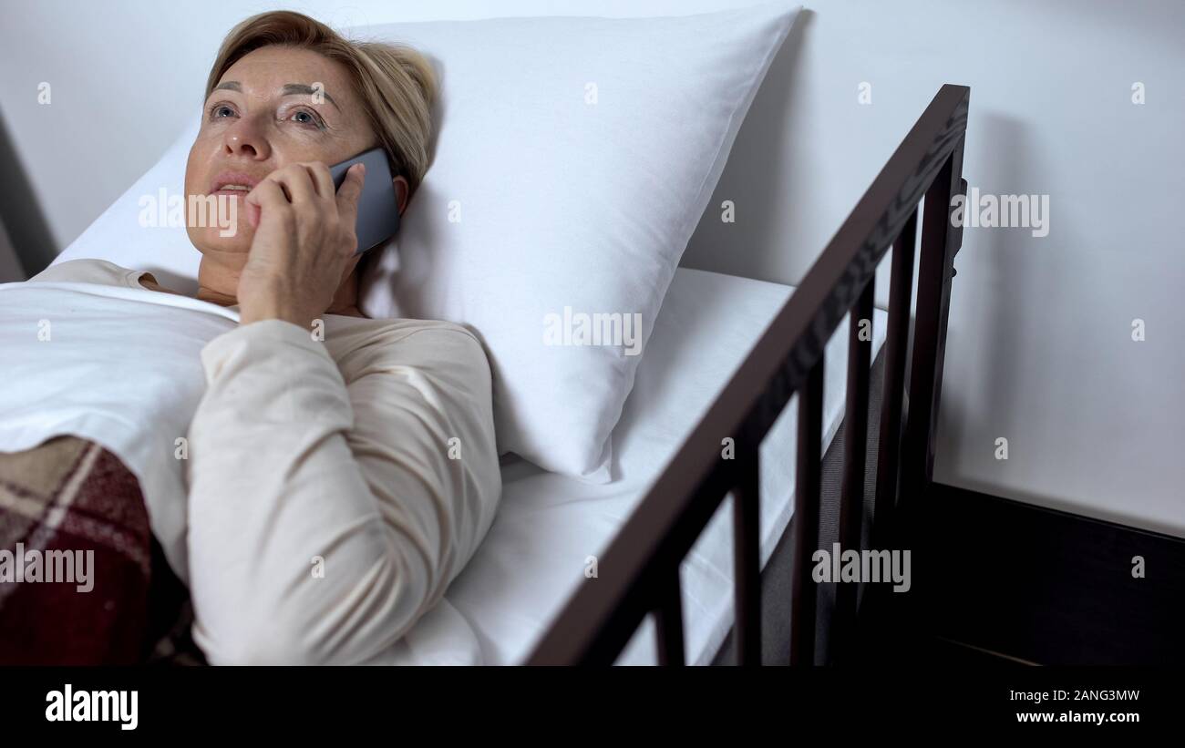 Female in hospital bed talking on smartphone, communicating with ...