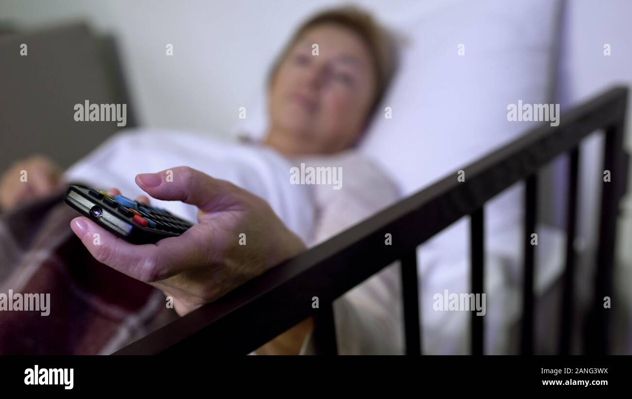 Woman lying on sickbed and switching channels on tv, personal ward in ...