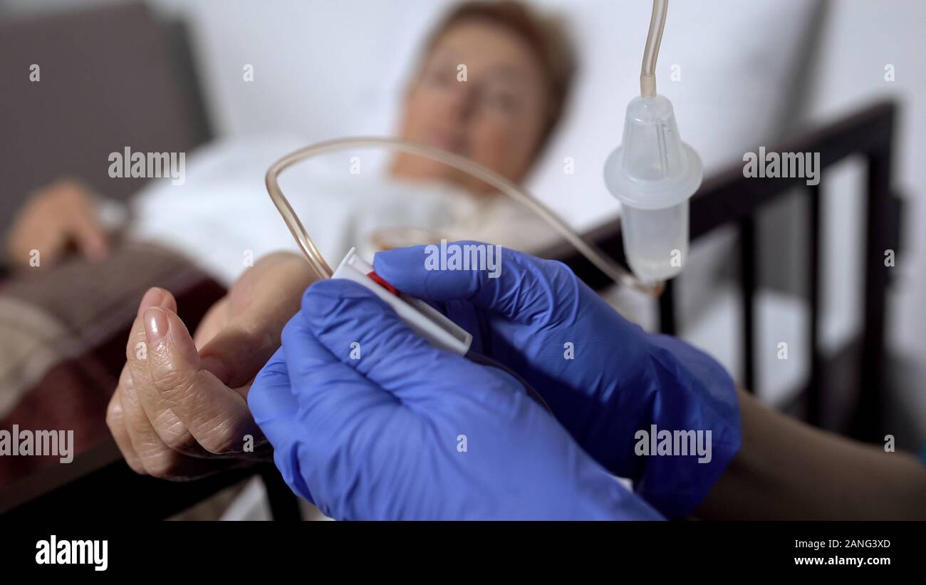 Doctor assistant stopping medication in drip, injection for female ...