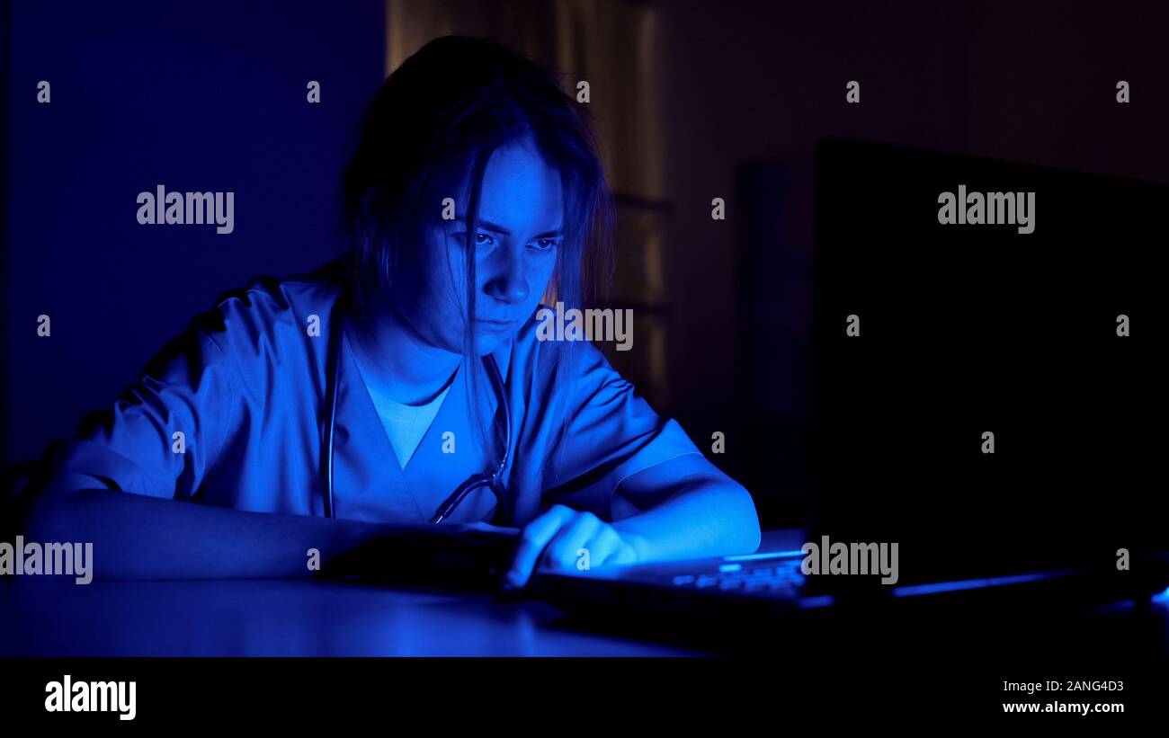 Sleepy nurse on duty sitting in dark room, exhausted by extra work in ...