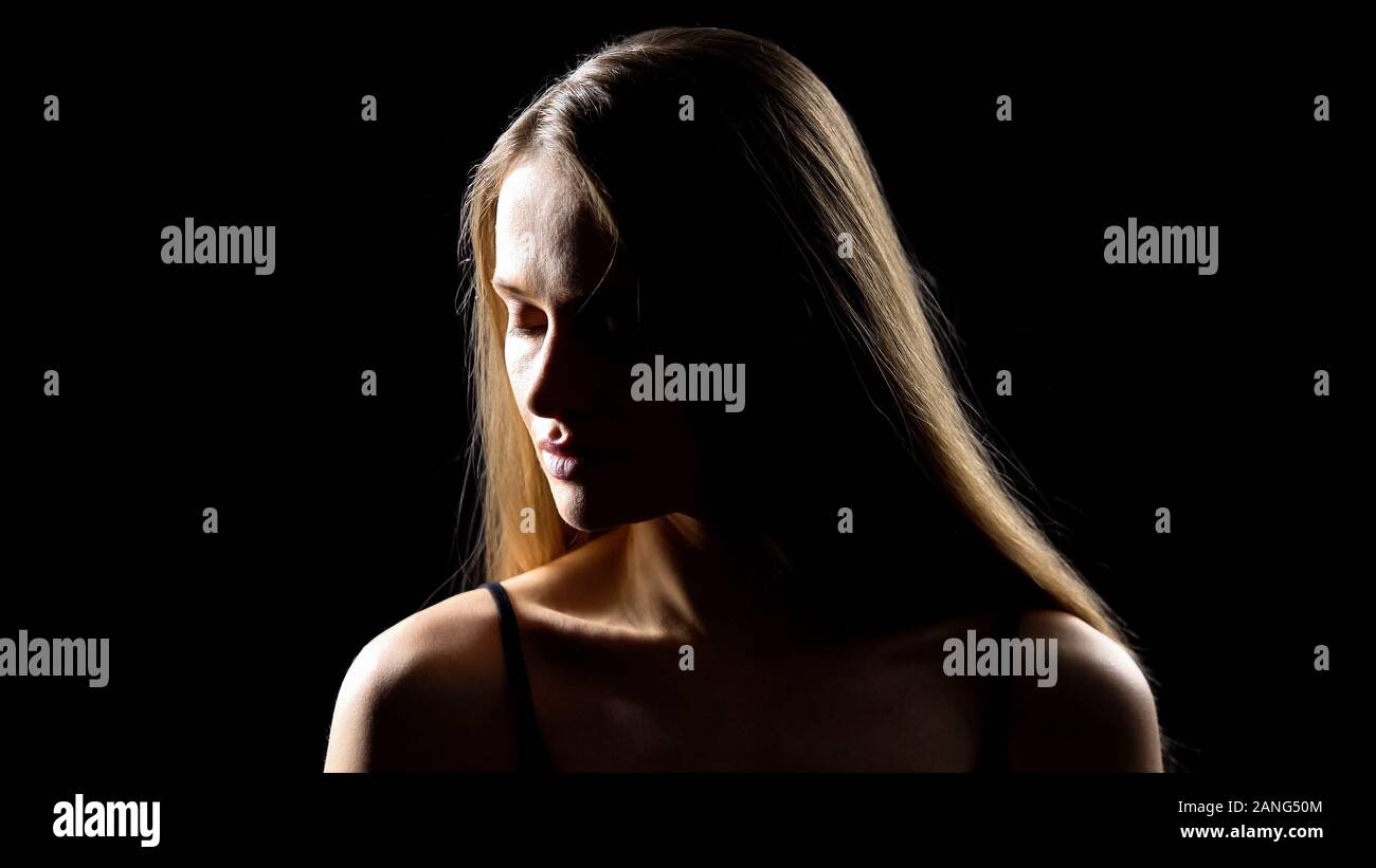 Beautiful young lady turning face to camera against black background ...