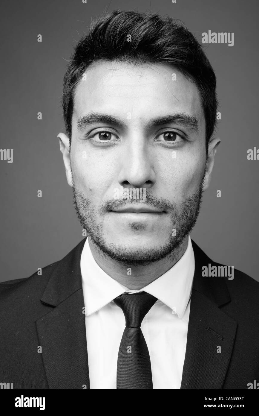Young handsome Hispanic businessman against gray background Stock Photo ...