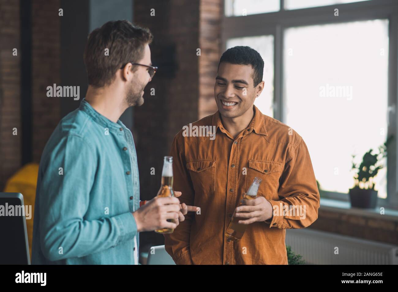 Positive happy young friends drinking beers together Stock Photo - Alamy