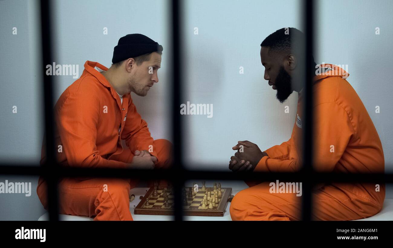 Caucasian and afro-american jail inmates playing chess in cell, prison ...