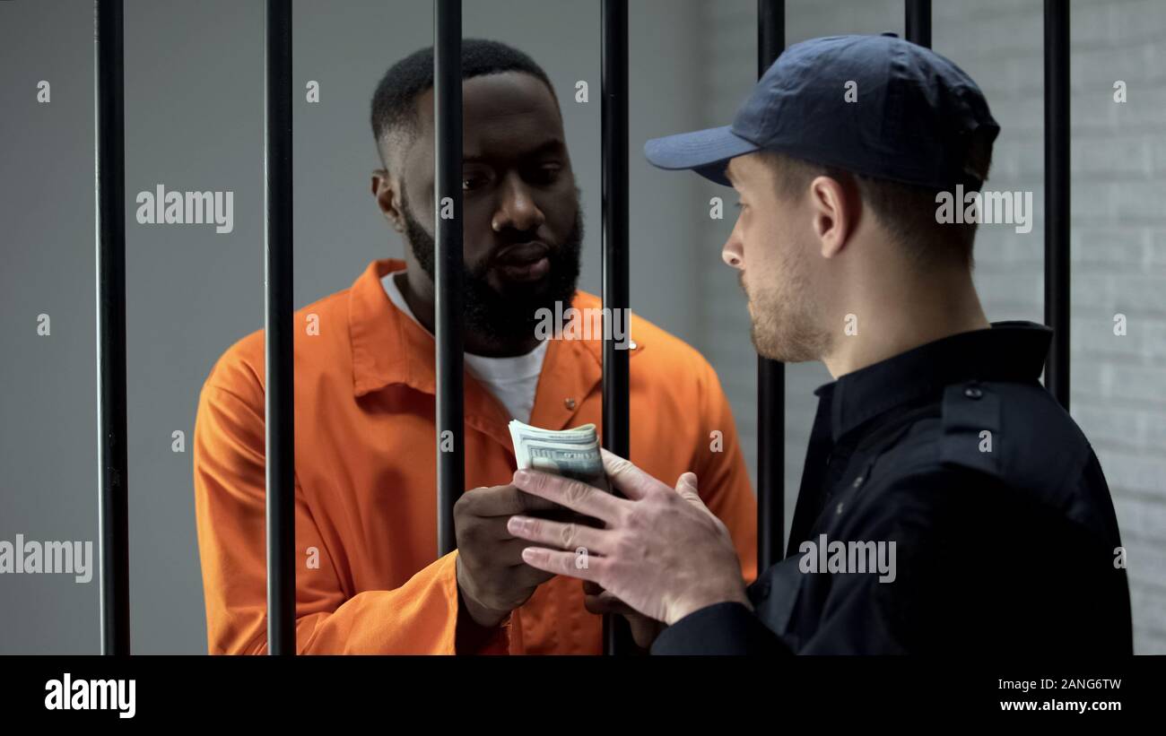 Prison guard taking dollar banknotes from afro-american criminal ...