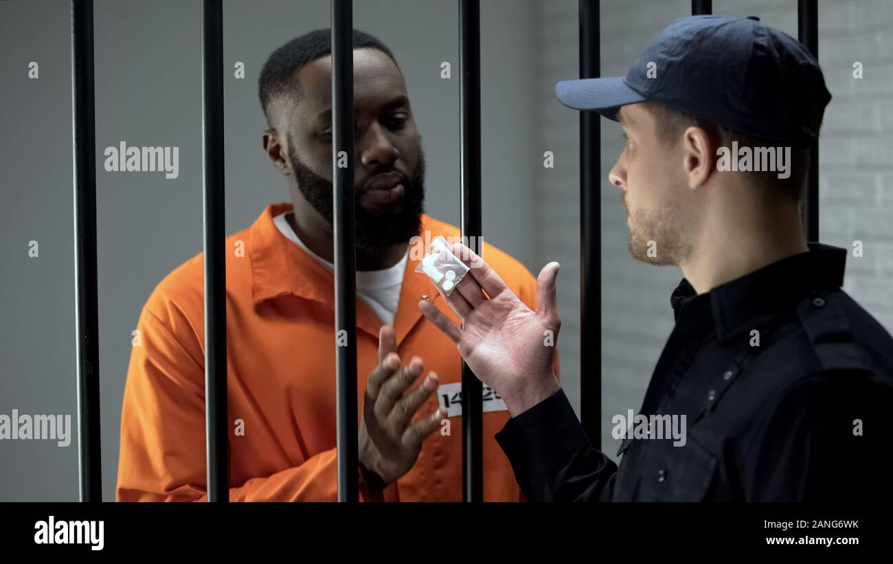 Jail guard giving african-american prisoner packet with pills, illegal ...